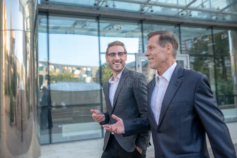 Two Smiling Business Partners Walking Outside, Having Friendly ...