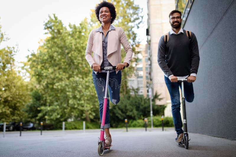Two Smiling Business People Driving Electric Scooter Going To Work ... Two Smiling Business People Driving Electric Scooter Going To Work ...
