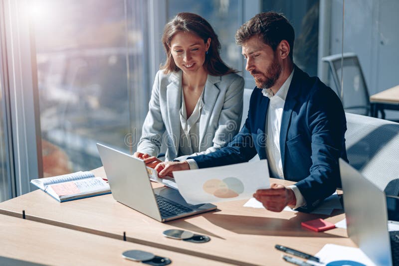 Two Smiling Business People in Modern Office Explaining Statistics Data ... Two Smiling Business People in Modern Office Explaining Statistics Data ...