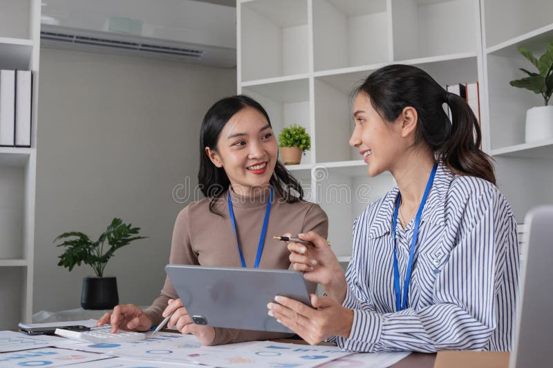 Two Smiling Businesswomen Discussing Work with Tablet in Modern Office ...