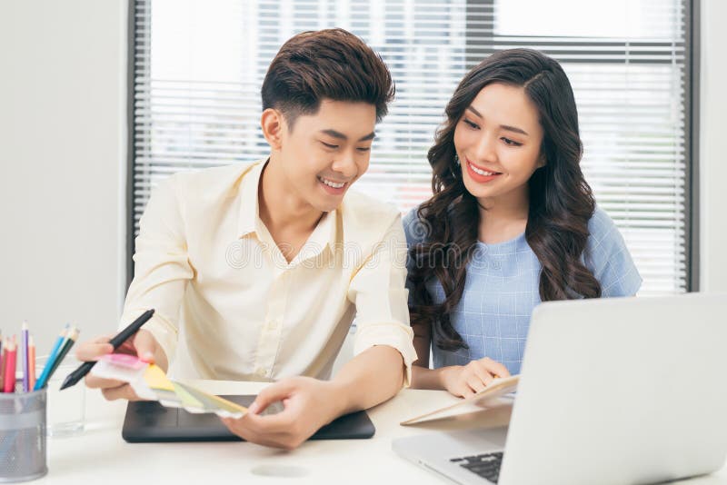 Two Smiling Casual Designers Working with Laptop while Sitting a Stock ... Two Smiling Casual Designers Working with Laptop while Sitting a Stock ...