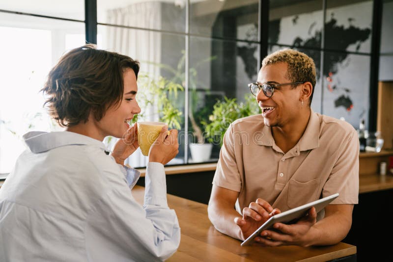 Two Smiling Colleagues with Tablet Talking during Coffee Break in ...