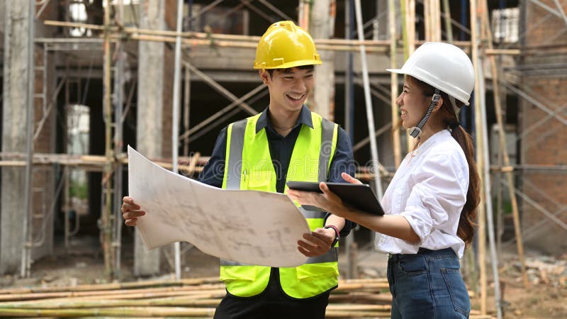 Two Smiling Engineers Wearing Safety Helmet Discussing, Planning ...