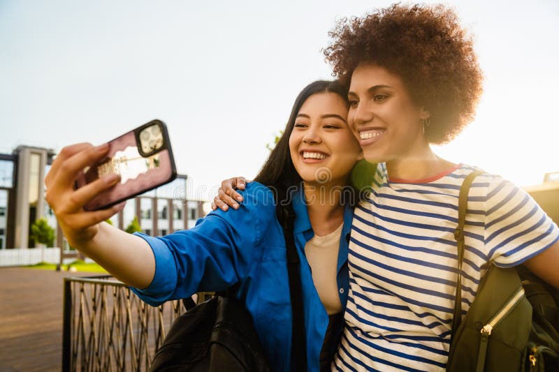 Two Smiling Female Students Taking Selfie while Standing Outdoors in ...