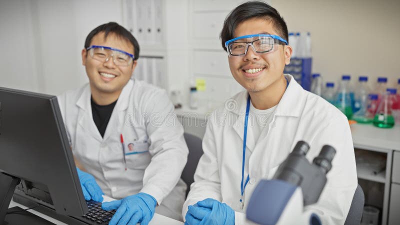 Two Smiling Men Wearing Lab Coats and Safety Glasses Working Together ...