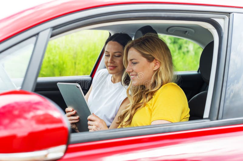 Two Smiling Women Sitting in a Car are Using a Tablet Stock Image ...