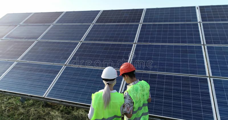 Two Solar Power Engineers Working on a Solar Farm. Drone Shot Stock ...