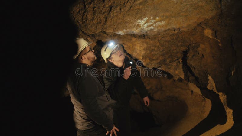 Two Speleologists with Flashlight Exploring the Cave`s Wall Stock ...