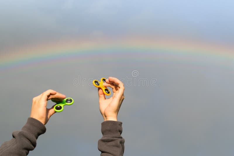 Two Spinners in the Hands on the Background of the Rainbow Stock Photo ...