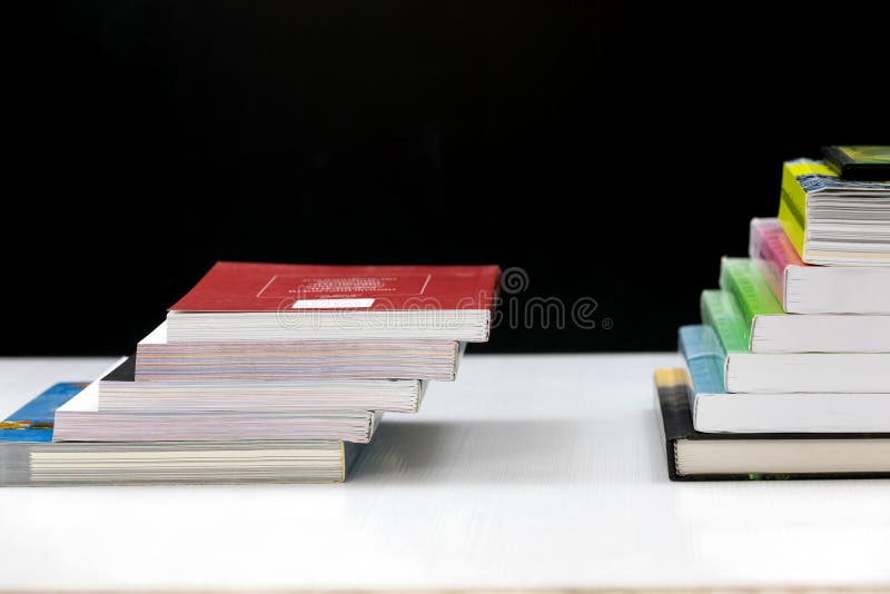 Two Stacks of Books are Placed on a White Table with a Black Background ...