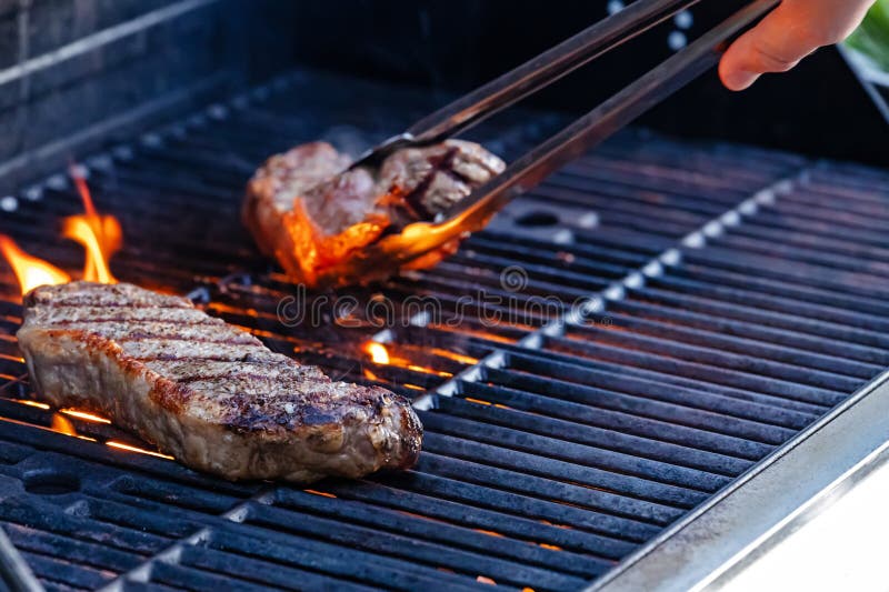 Two Steaks Sizzle Over an Open Flame on a Backyard Grill, Close-up ...