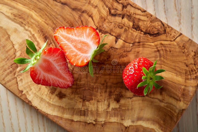 Two Strawberries on a Cutting Board Made from Olive Wood, One Cut in ...