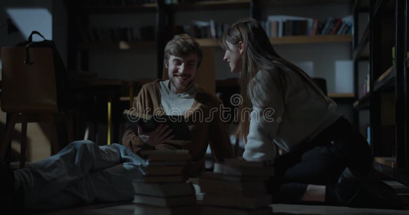 Two Students Communicate and Read a Book in a Cozy Evening Library ...