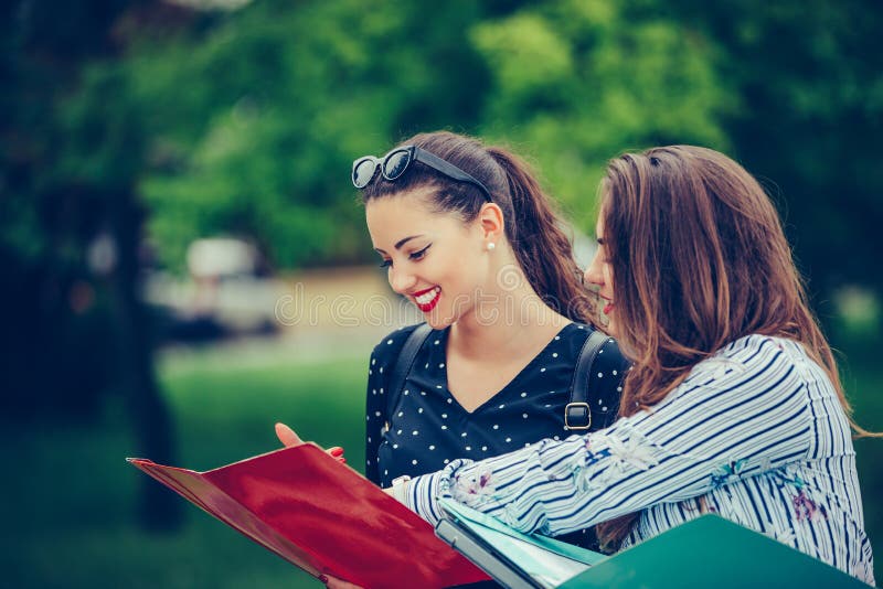 Two Students Learning Reading a Notebook and Commenting in the Street ...