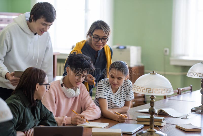 Two Students Pointing at Notes of Teenage Guy while Choosing Name for ...