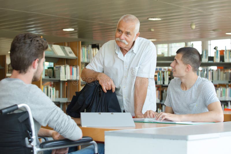 Two Students Reading in Library with Senior Teacher Stock Image - Image ...