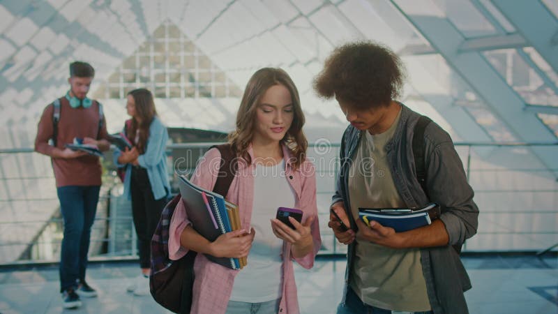 Two Students Talking and Using Smartphone in the College Hallway Stock ...