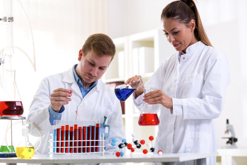 Two Young Students Working at Lab and Taking Notes Off Chamical Stock ...