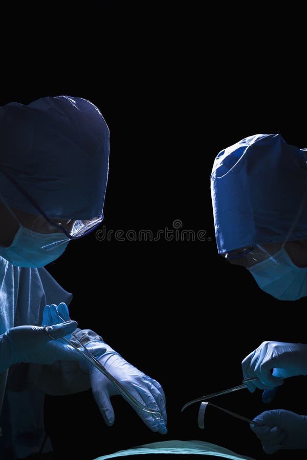 Two Surgeons Looking Down, Working, and Holding Surgical Equipment with ...