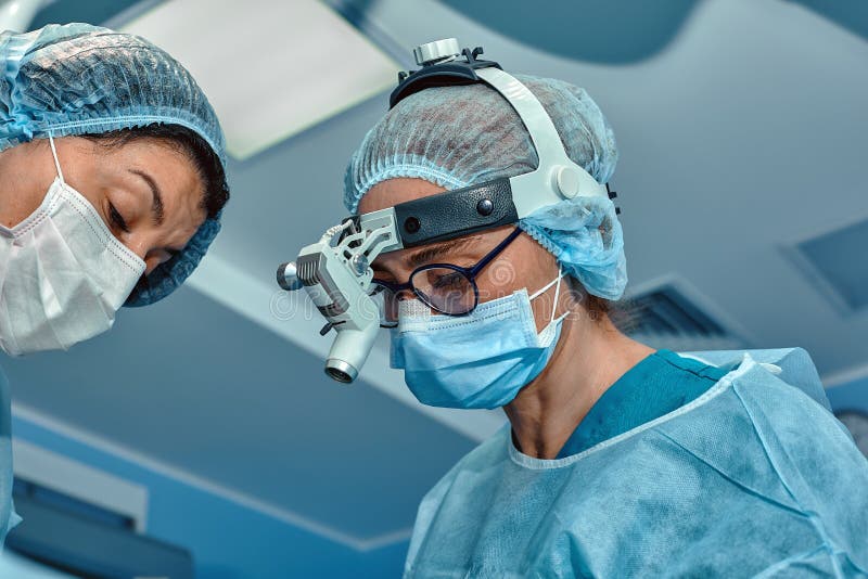 Two Surgeons in Protective Uniform during the Operation, on Background ...