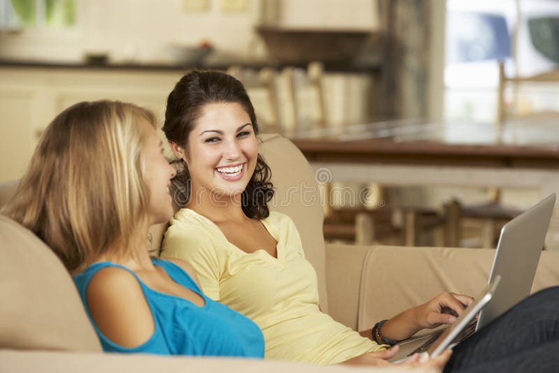 Two Teenage Girls Sitting on Sofa at Home Using Tablet Computer and ...