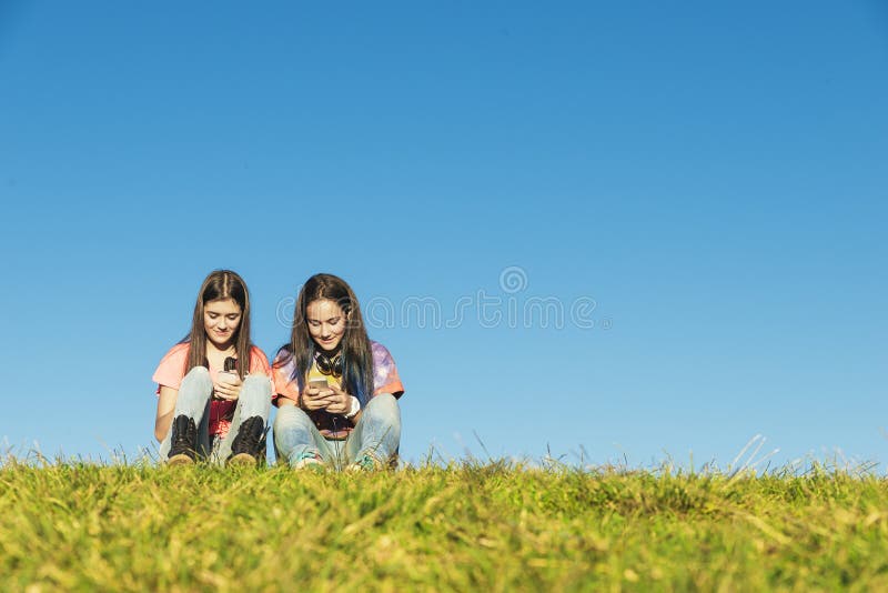 Two Teenage Girls Using Mobile in Park Stock Image - Image of ...