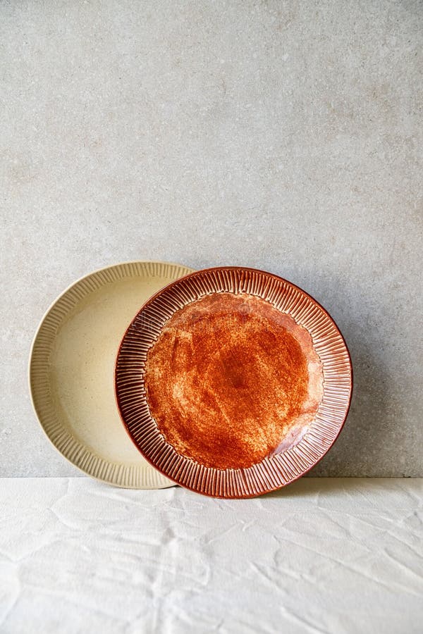Two Textured Ceramic Plates, One Red and One Beige, Placed on a Light ...