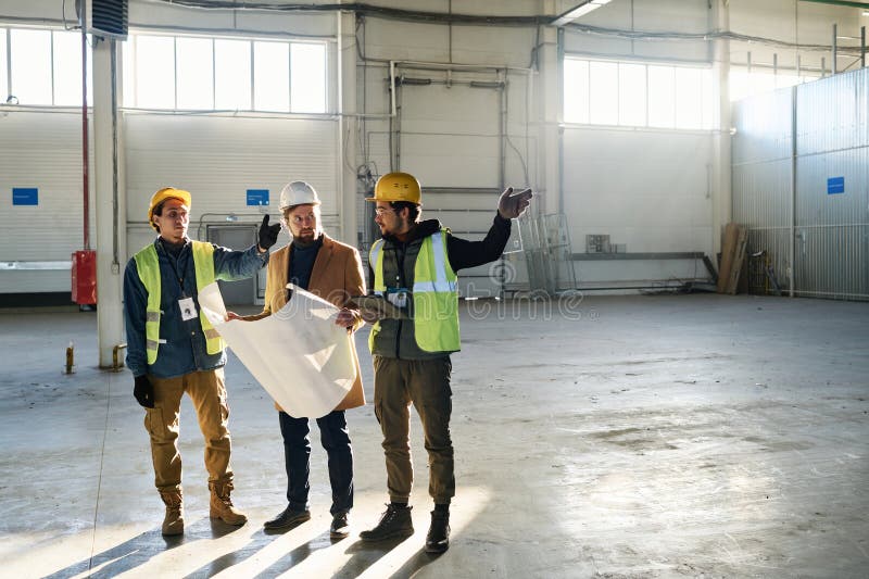Two of Three Young Engineers Pointing Aside while Explaining Something ...