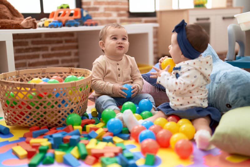 Two Toddlers Playing with Balls Sitting on Floor at Kindergarten Stock ...