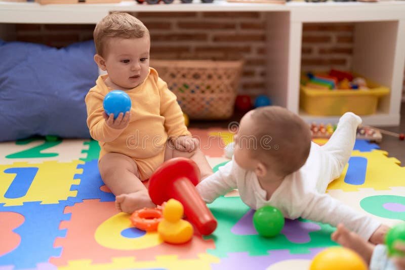 Two Toddlers Playing with Balls Sitting on Floor at Kindergarten Stock ...