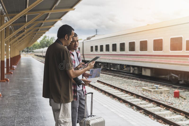 Two Travelers with Tablet and Map Talking Together in Train Station ... Two Travelers with Tablet and Map Talking Together in Train Station ...