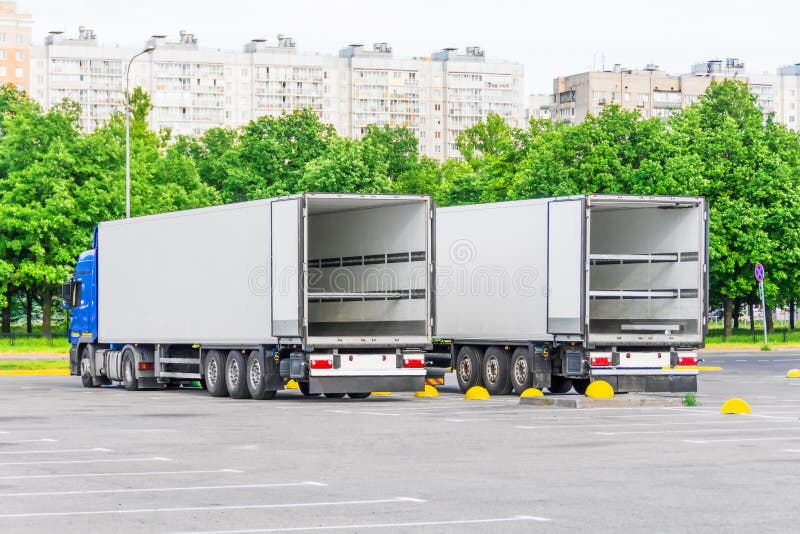 Two Trucks in a Parking Lot with an Empty Container Trailer Open Gates ...