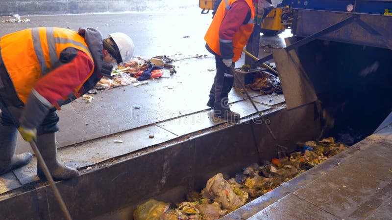 Two Unrecognized Men are Sorting the Garbage that is Slowly Moving Up ...