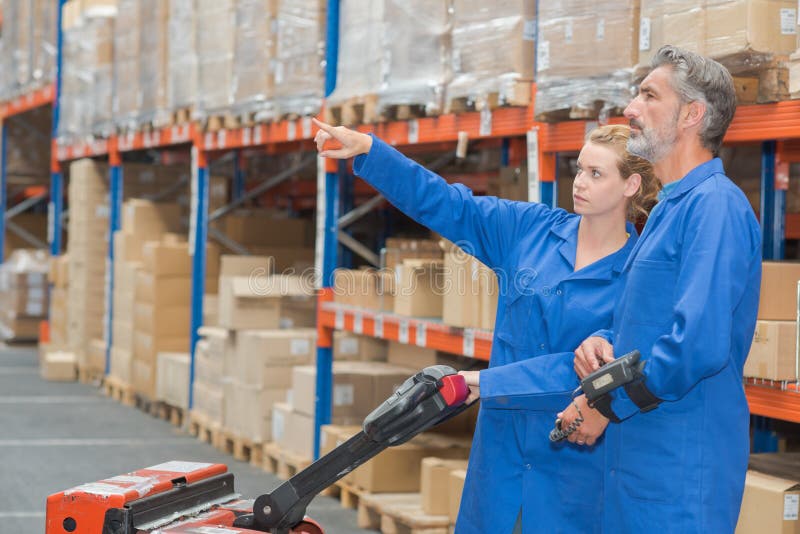 Two Warehouse Workers with Pallet Truck Pointing Stock Photo - Image of ...