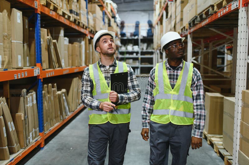 Two Warehouse Workers are Walking through the Facility, Engaged in ...
