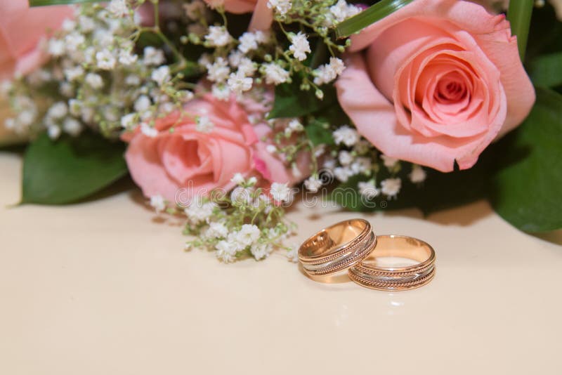 Two Wedding Rings Lie the Table.Beckett Pink Roses. Stock Image - Image ...