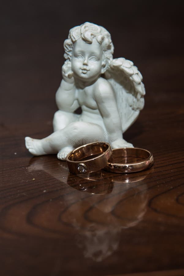 Two Wedding Rings Lie on the Table.a Sculpture Angel. Stock Image ...