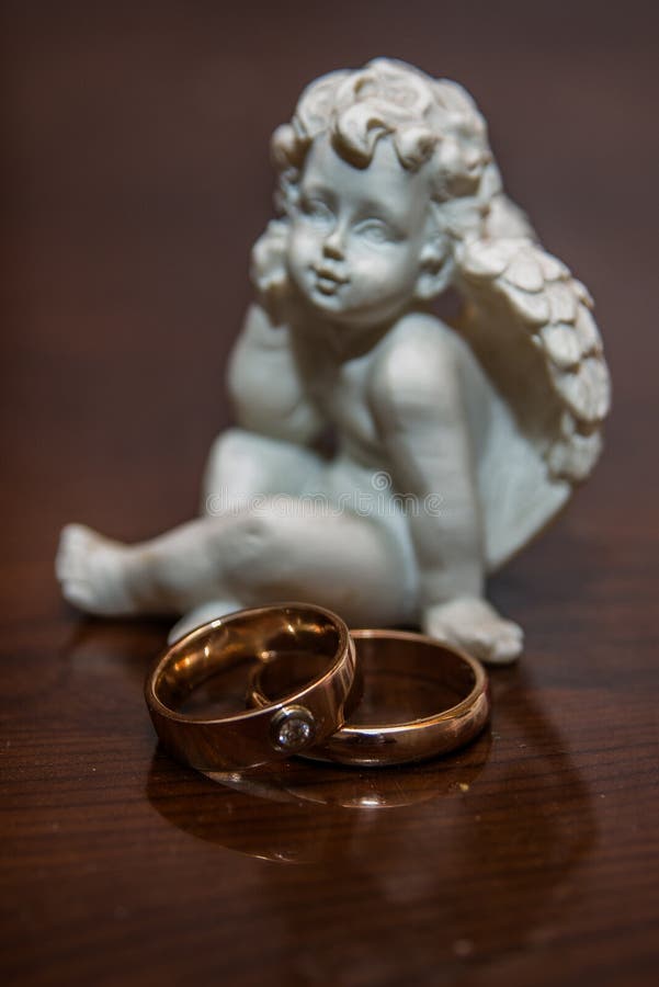 Two Wedding Rings Lie on the Table.a Sculpture Angel. Stock Photo ...
