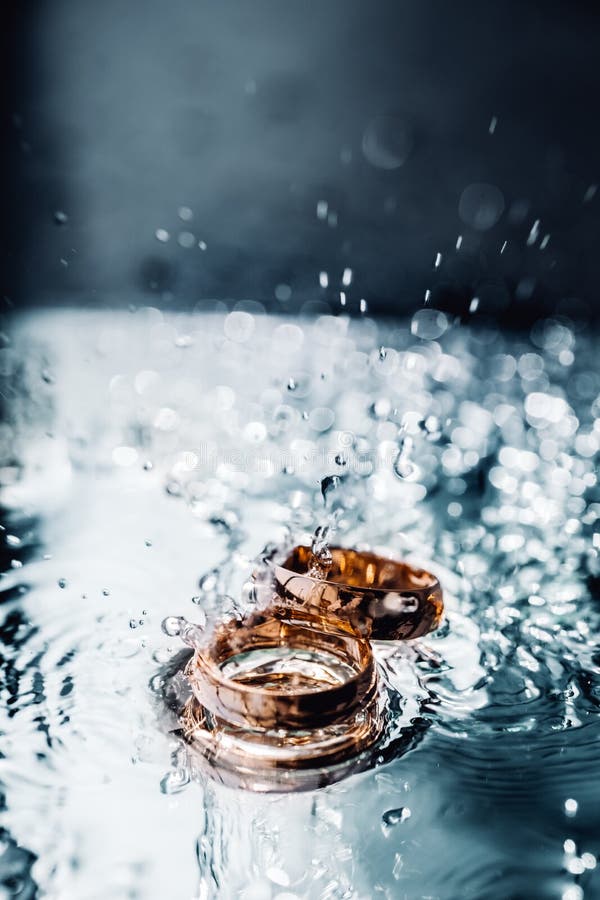 Two Wedding Rings in Water Splashes Laying on Flat Surface Stock Image ...