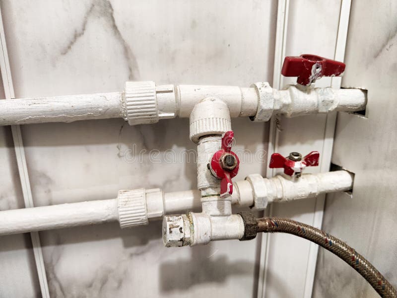 Plumbing System with White Pipes and Red Valves in an Indoor Setting ...