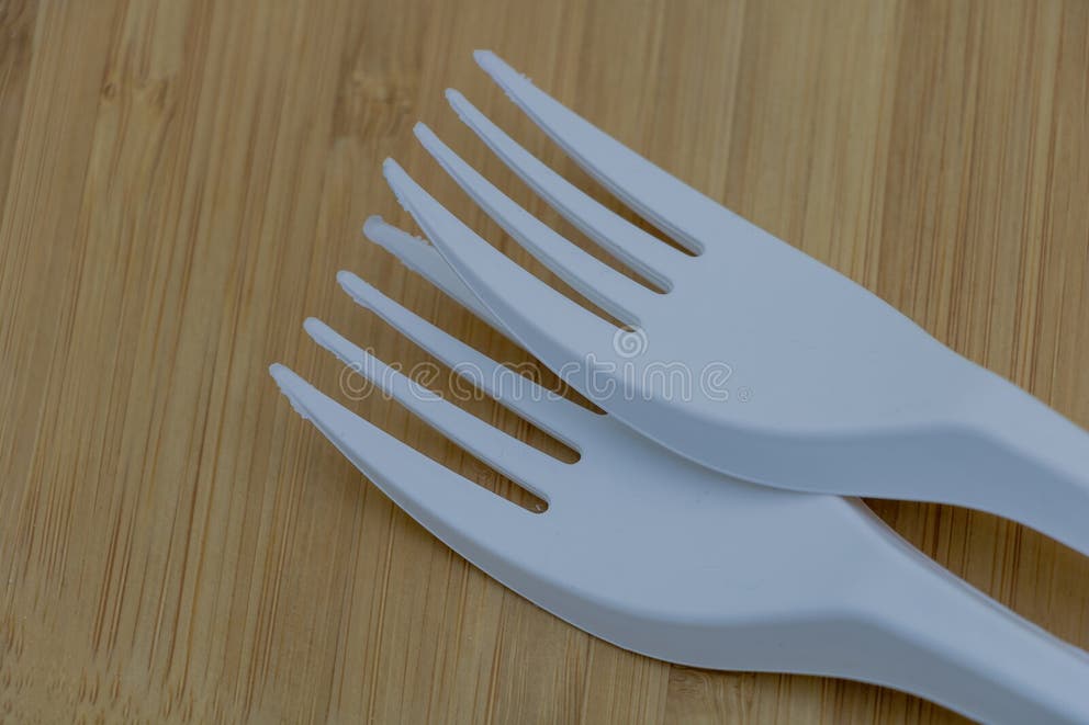 Two White Plastic Fork Pieces Stacked on Top of Each Other on a Bamboo ...
