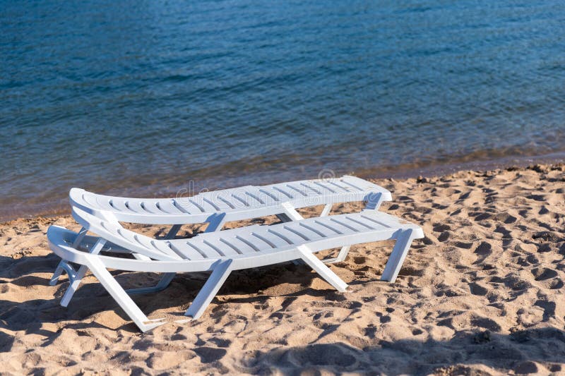 Two White Plastic Sun Loungers Stand on a Sandy Beach Stock Photo ...