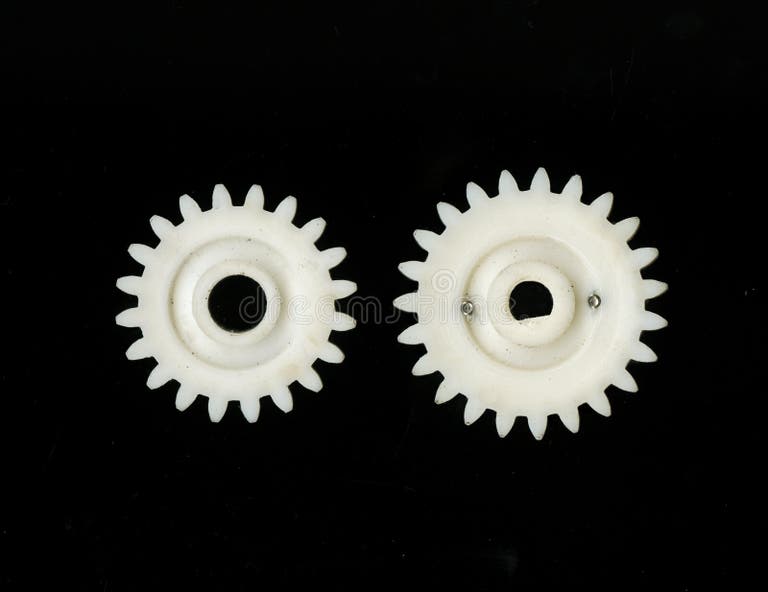Two White Plastic Toothed Gears of Different Sizes on a Black ...