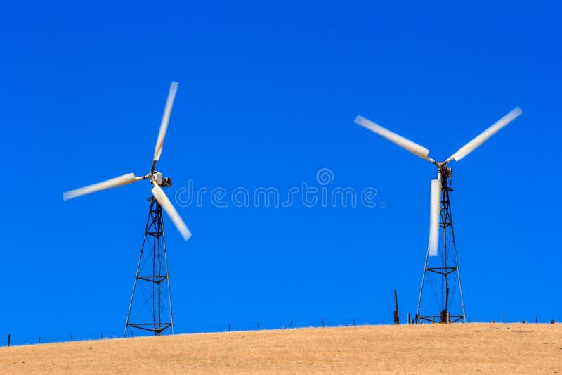 Two Wind Turbines are on a Hillside, One of Which is Spinning Stock ...
