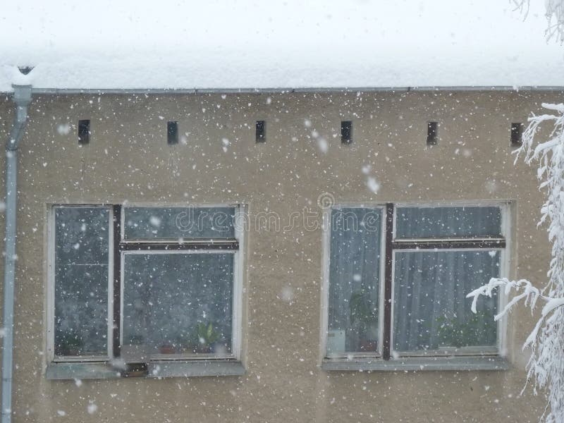 Two Windows on a Building Facade during a Snowfall. Snowflakes Falling ...