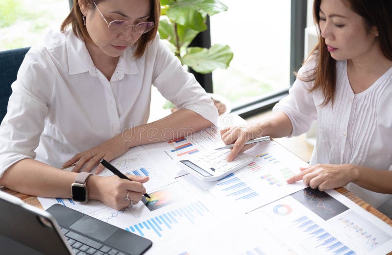 Two Women Analyzing Documents while Sitting on a Table in Office. Woman ...