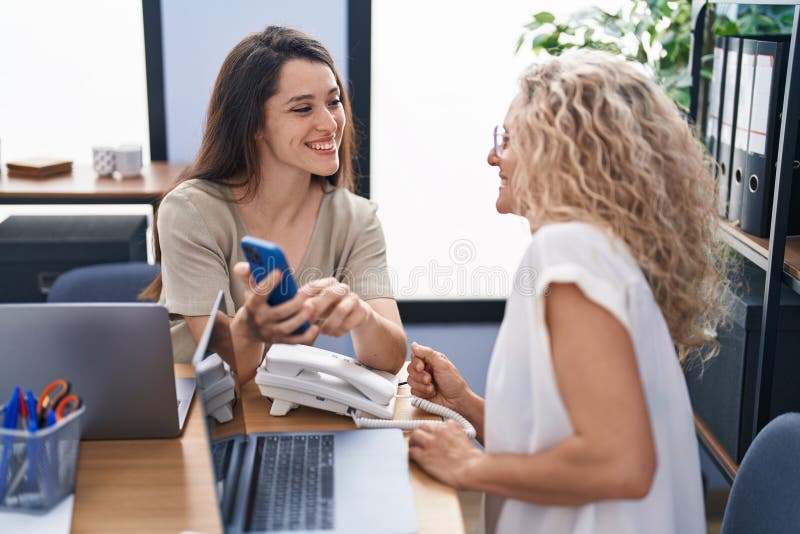 Two Women Business Workers Using Smartphone Working at Office Stock ...