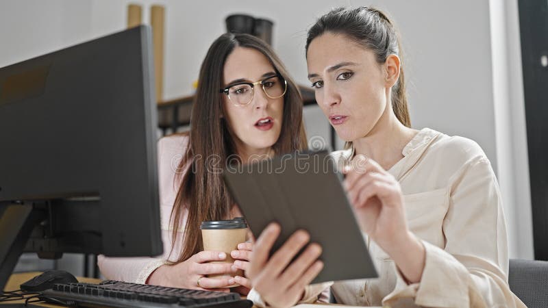 Two Women Business Workers Using Touchpad Drinking Coffee at Office ...