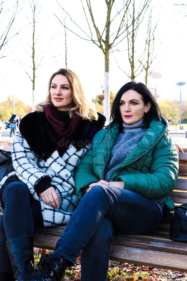 Two Women in Coats Sitting Outside on a Bench Stock Photo - Image of ...
