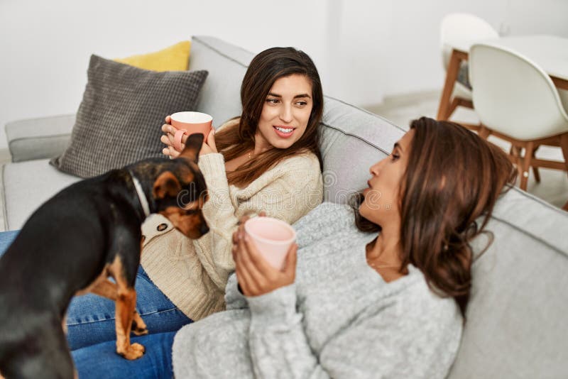 Two Women Drinking Coffee Sitting on Sofa with Dog at Home Stock Photo ...